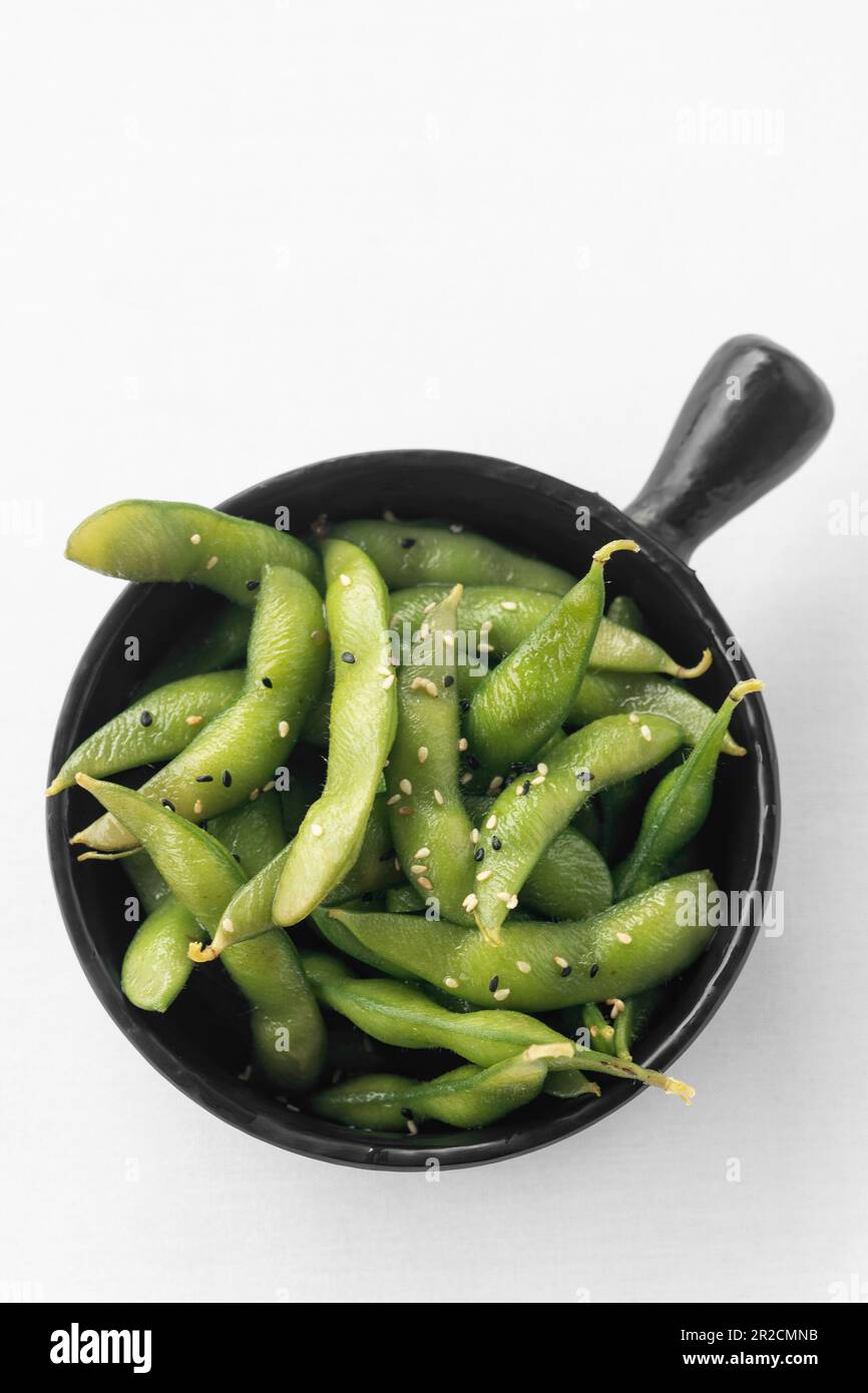 japanese edamame beans snack in black ceramic bowl on white background ...