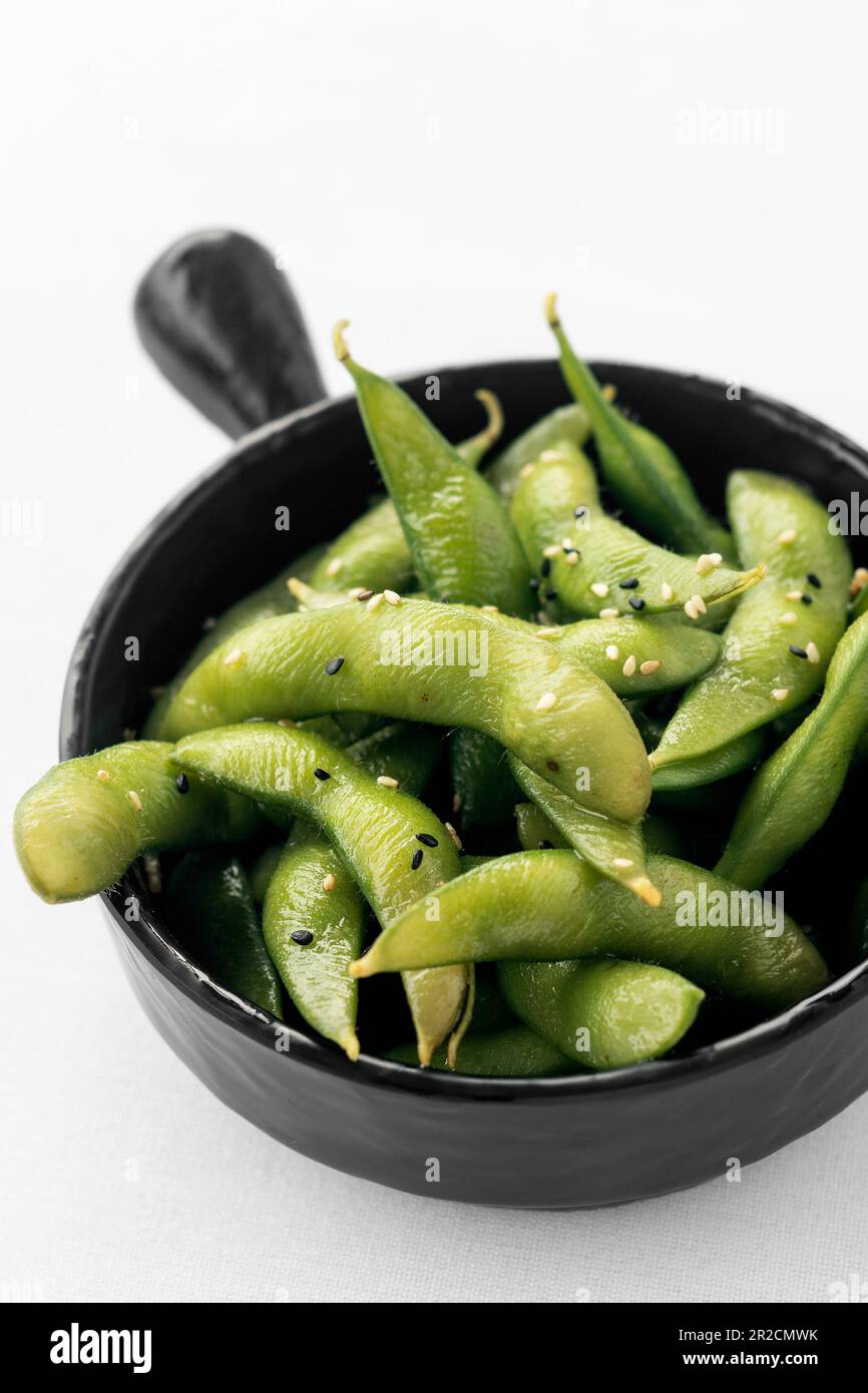 japanese edamame beans snack in black ceramic bowl on white background ...