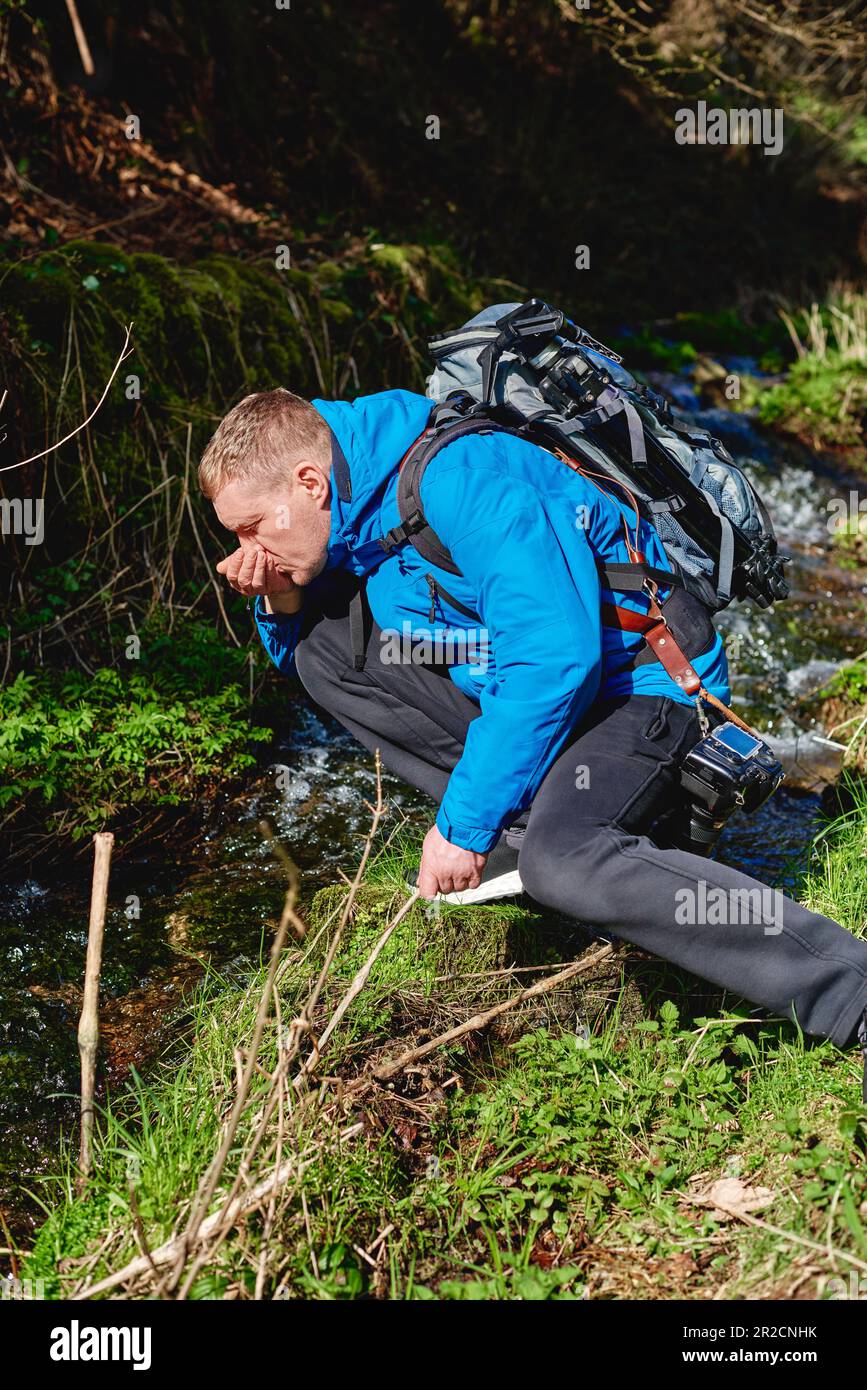 Hiker drinking stream water in mountain. Adult man drinking water from ...