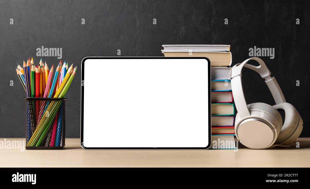Tablet with colorful pencils and stack of books. With blank screen for ...