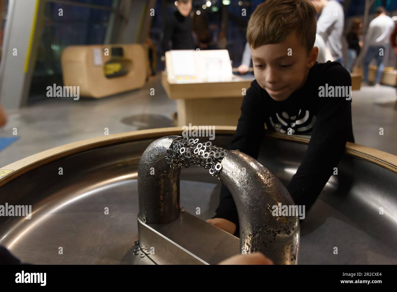A boy plays with metal objects on a stand with a large magnet Stock ...
