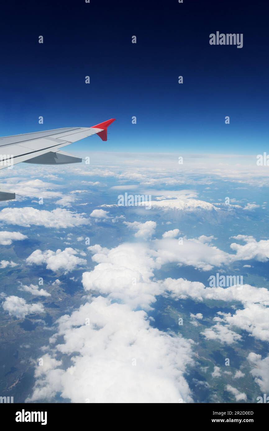 A view through an airplane window during flight. Visible wing, clouds ...