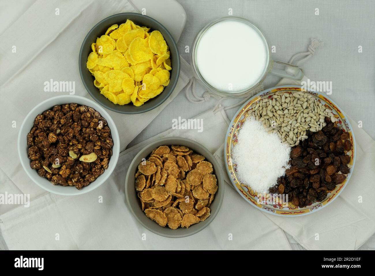 Variety of breakfast cereals, muesli and milk in bowls on a light ...