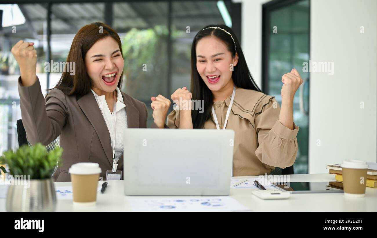 Two excited and cheerful millennial Asian businesswomen are rejoicing ...