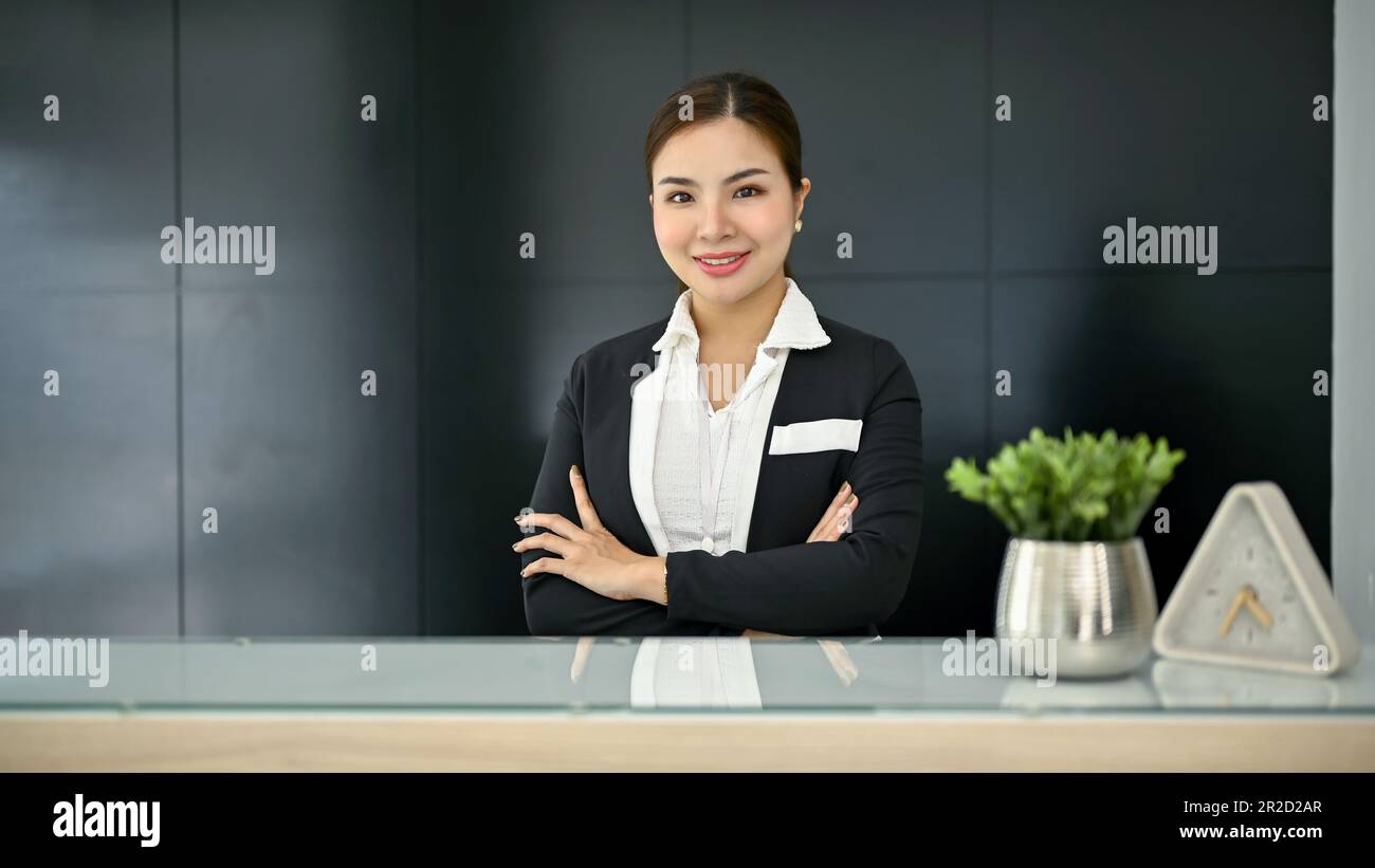 Attractive and confident millennial Asian female receptionist stands at ...