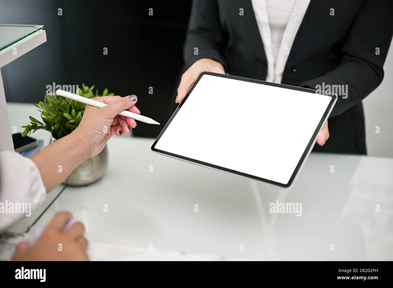 Close-up image of a female receptionist is handing a digital tablet to ...