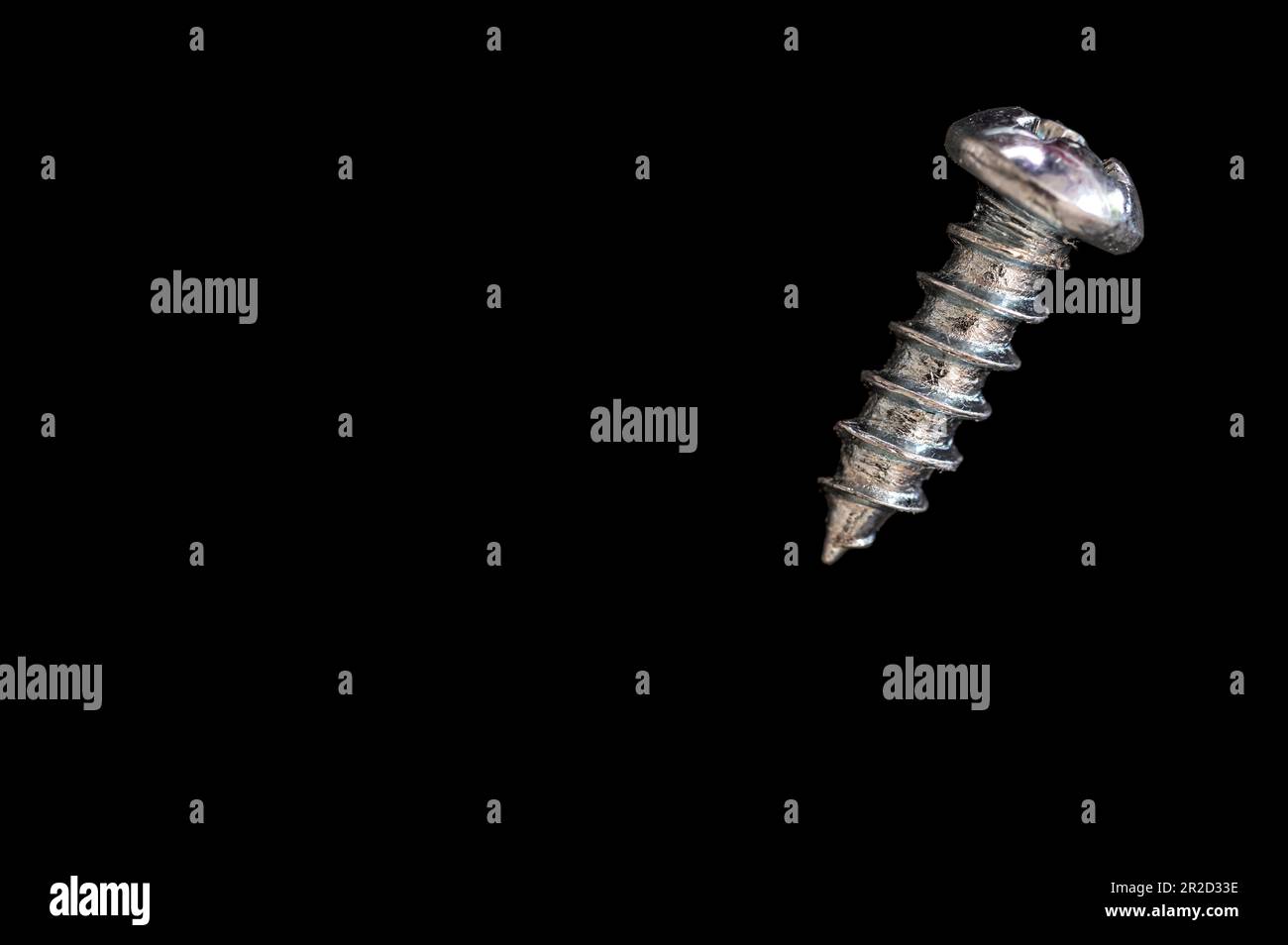 Small round head screw with a sharp point in extreme close up on a ...