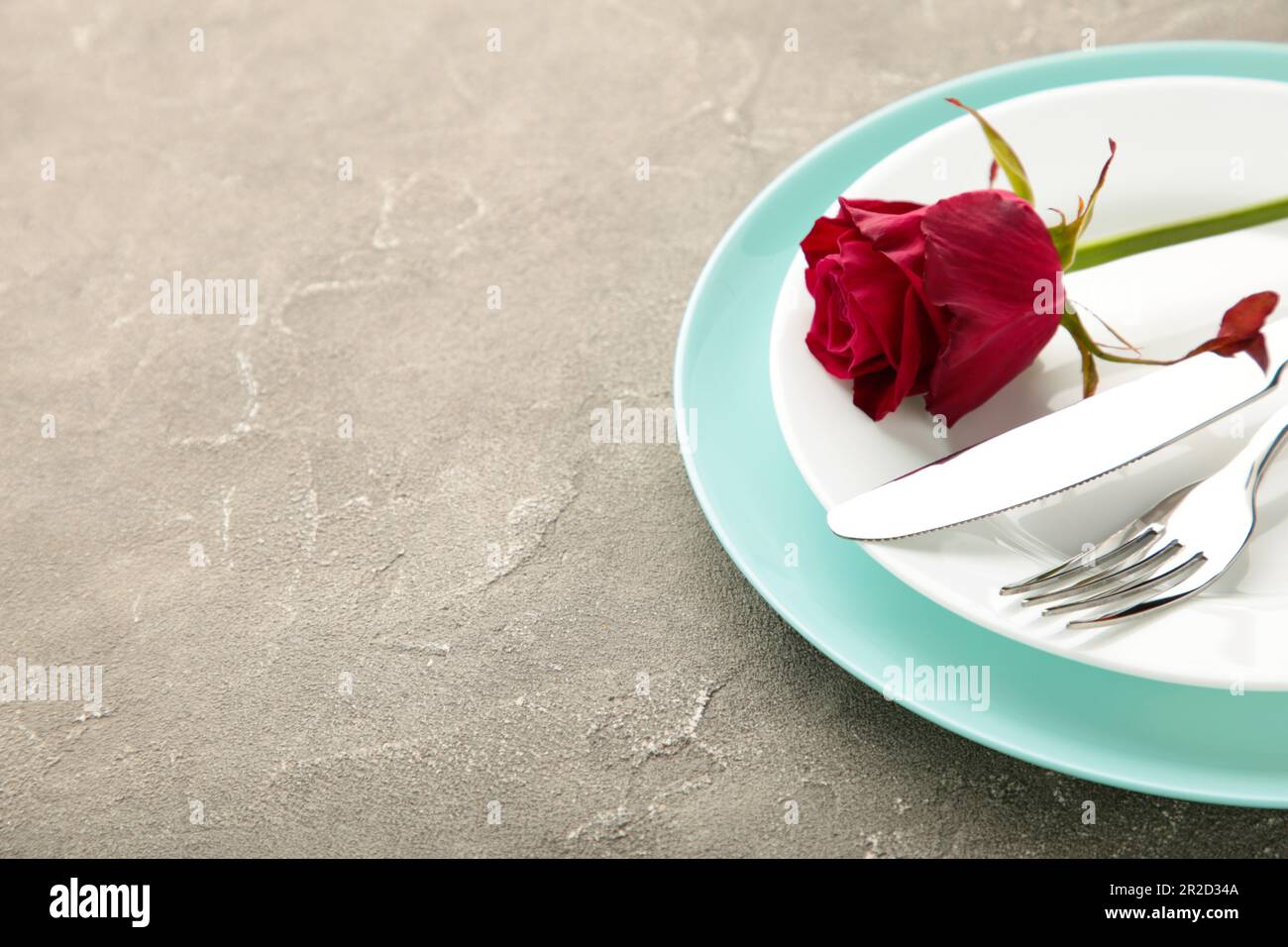 Romantic restaurant table setting with red rose on plates. Valentine's ...