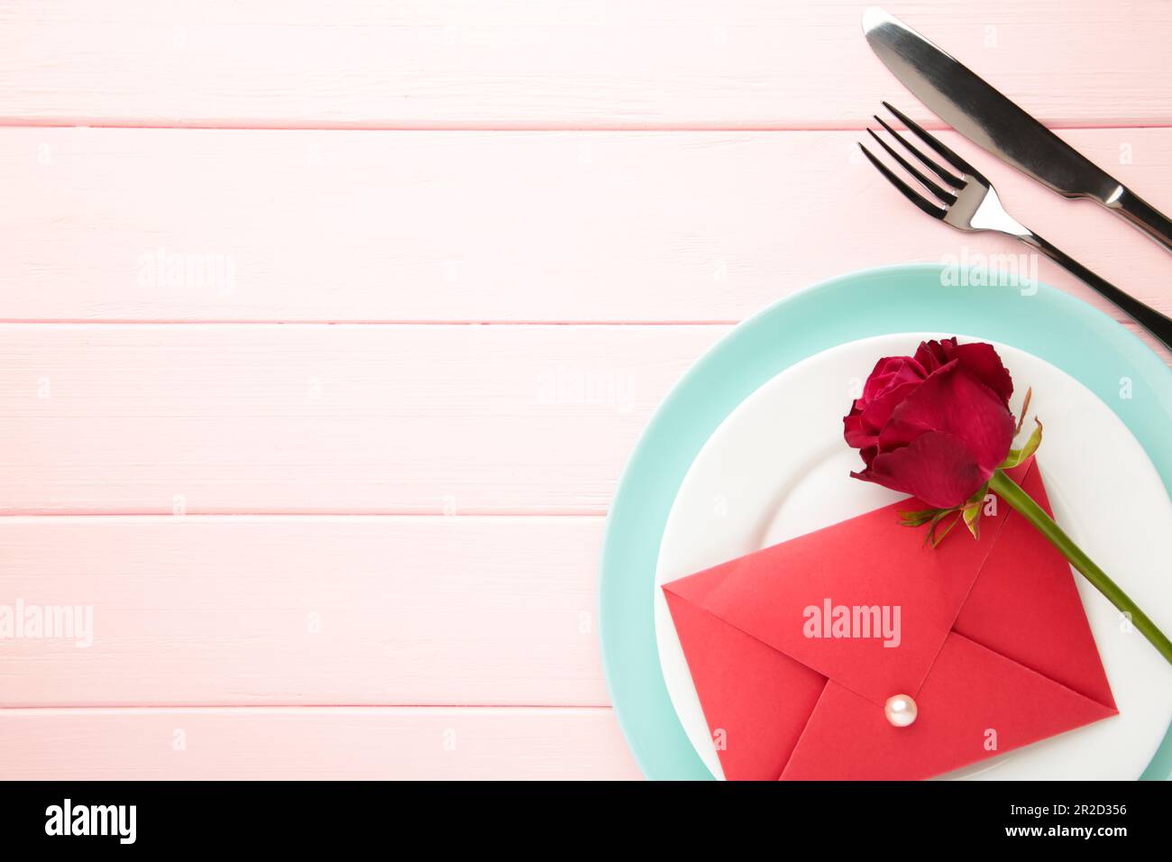 Romantic restaurant table setting with red rose on plates. Valentine's ...