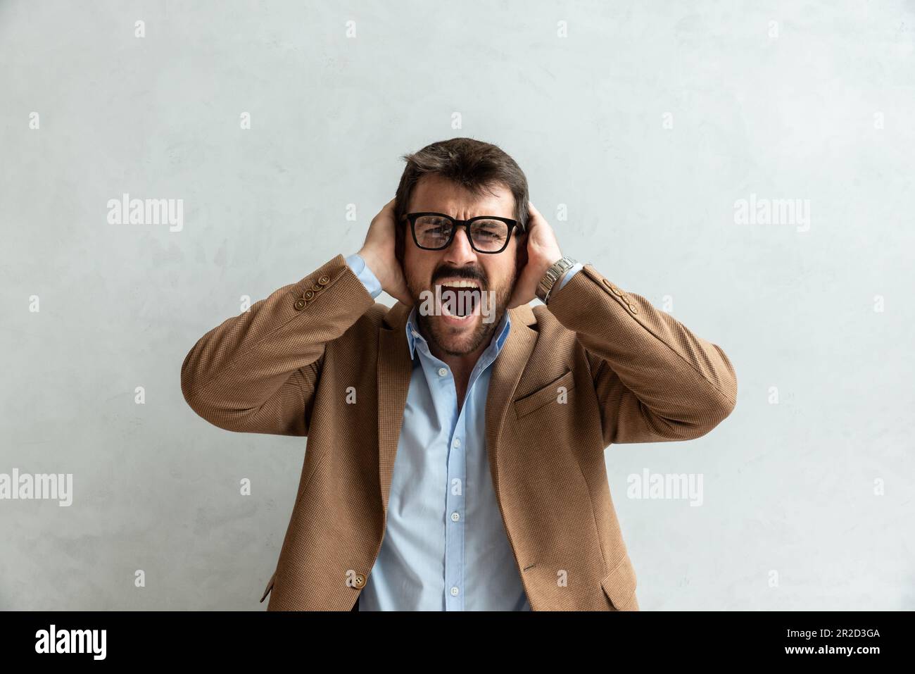 Young business man office worker covered his ears with his hands and ...