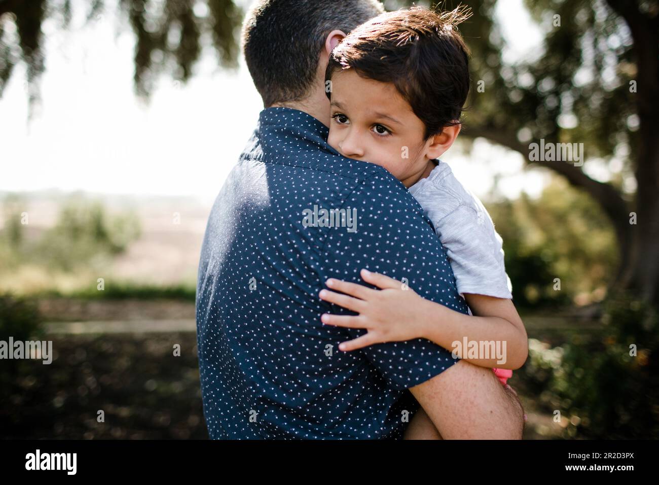 Autistic Boy Hugging Dad While Standing Under Tree Stock Photo - Alamy