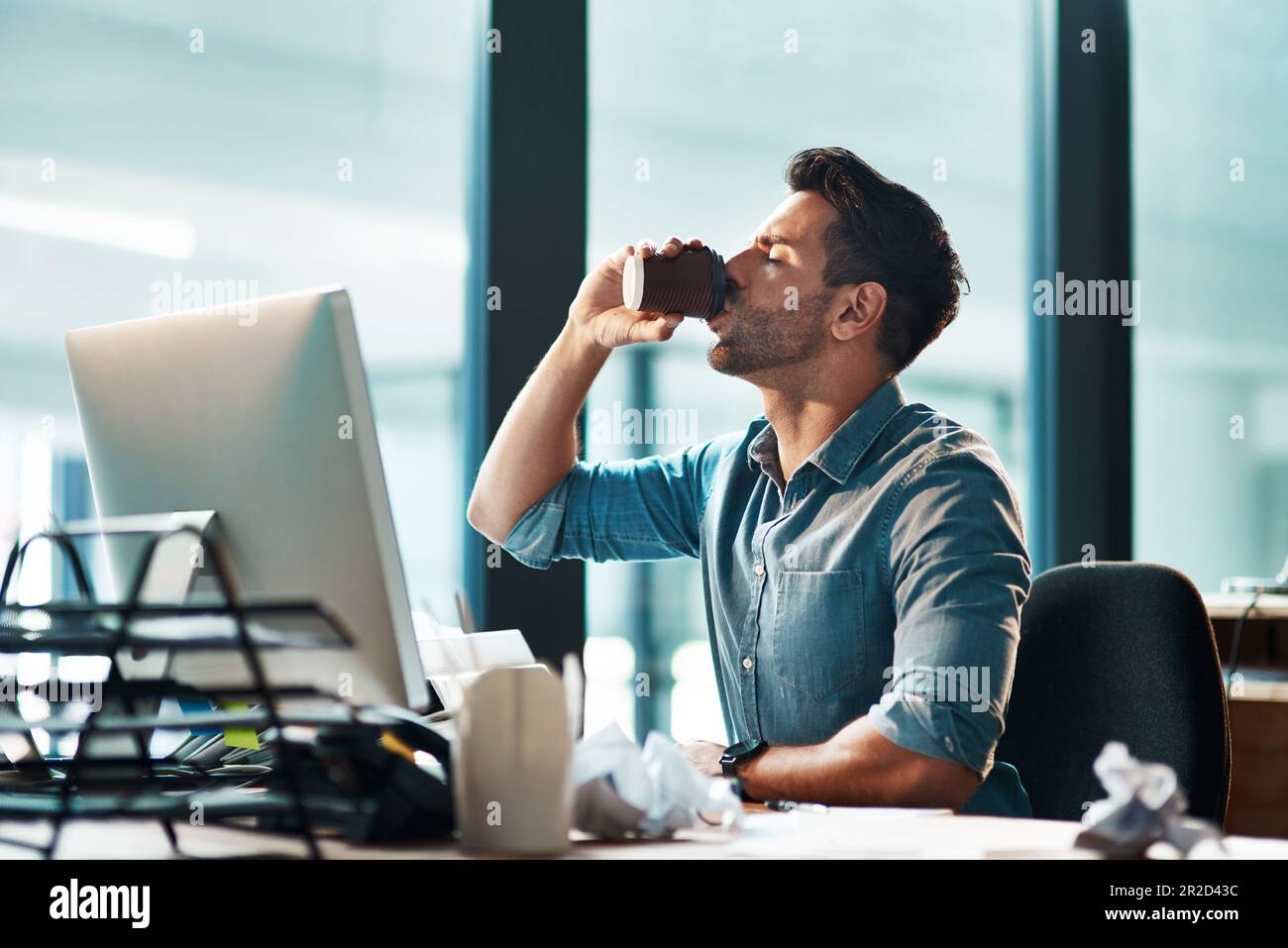 Business man drinking coffee in office at computer in startup agency ...