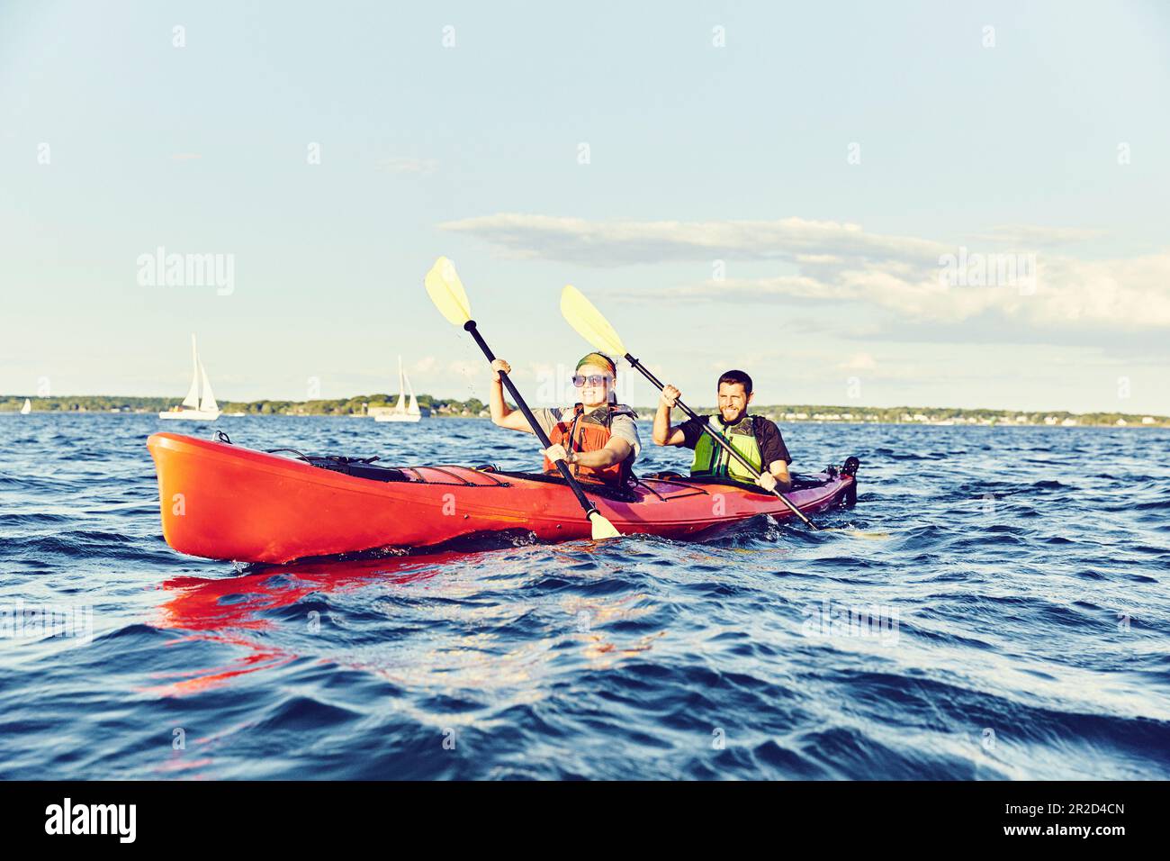 Young couple in tandem kayak paddle through Casco Bay at sunset Stock ...