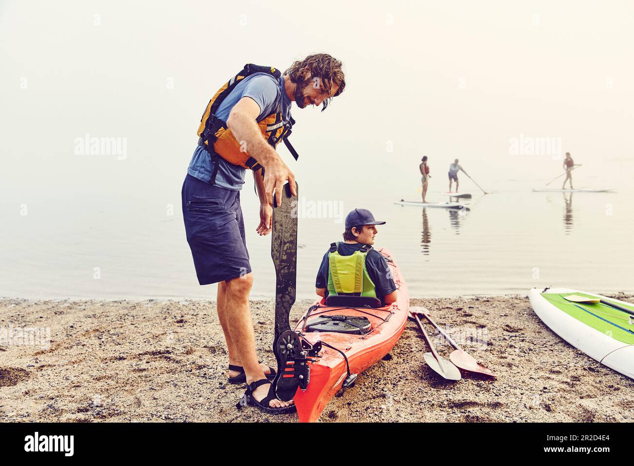 Instructor helps his young student get ready for a kayaking trip Stock Photo - Alamy