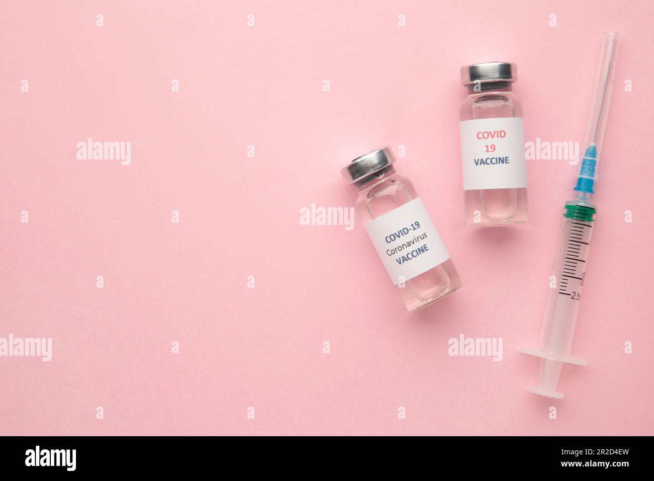 Coronavirus COVID-19 vaccine vials and syringe on pink with copy space ...
