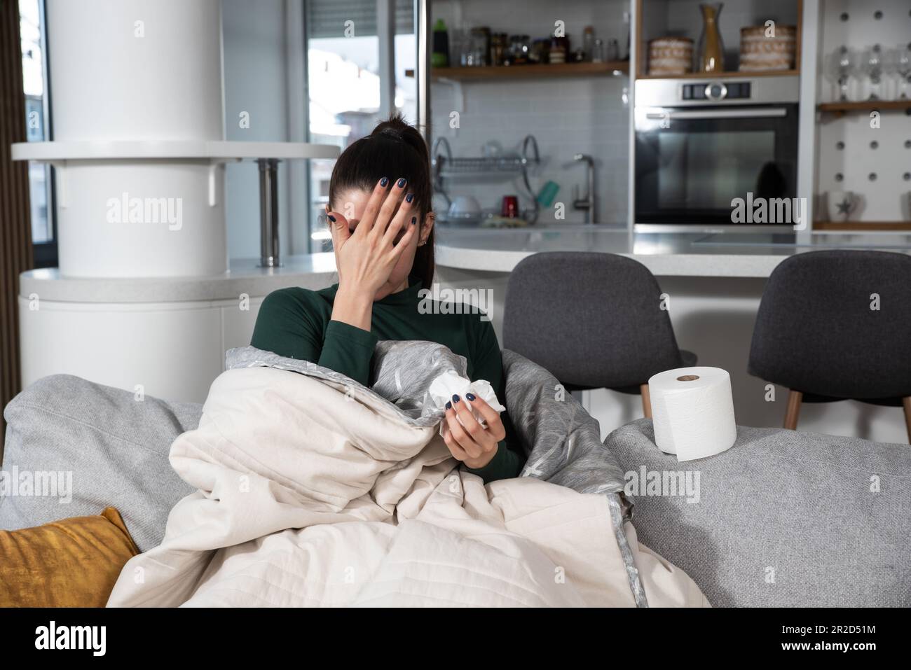 Ill upset young woman sitting on sofa covered with blanket freezing ...