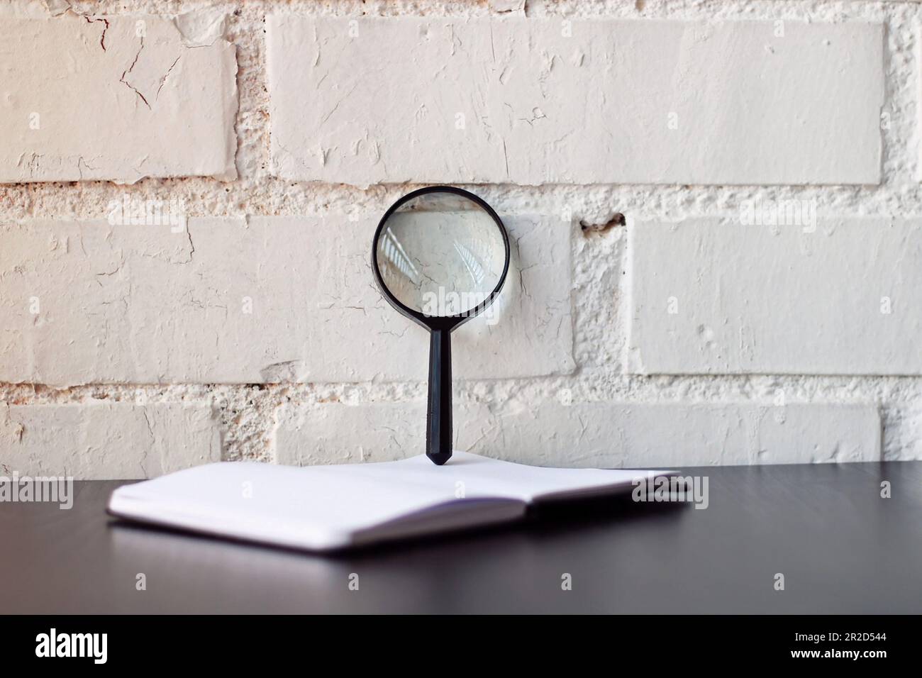 Magnifying glass on top of a black notebook Stock Photo - Alamy