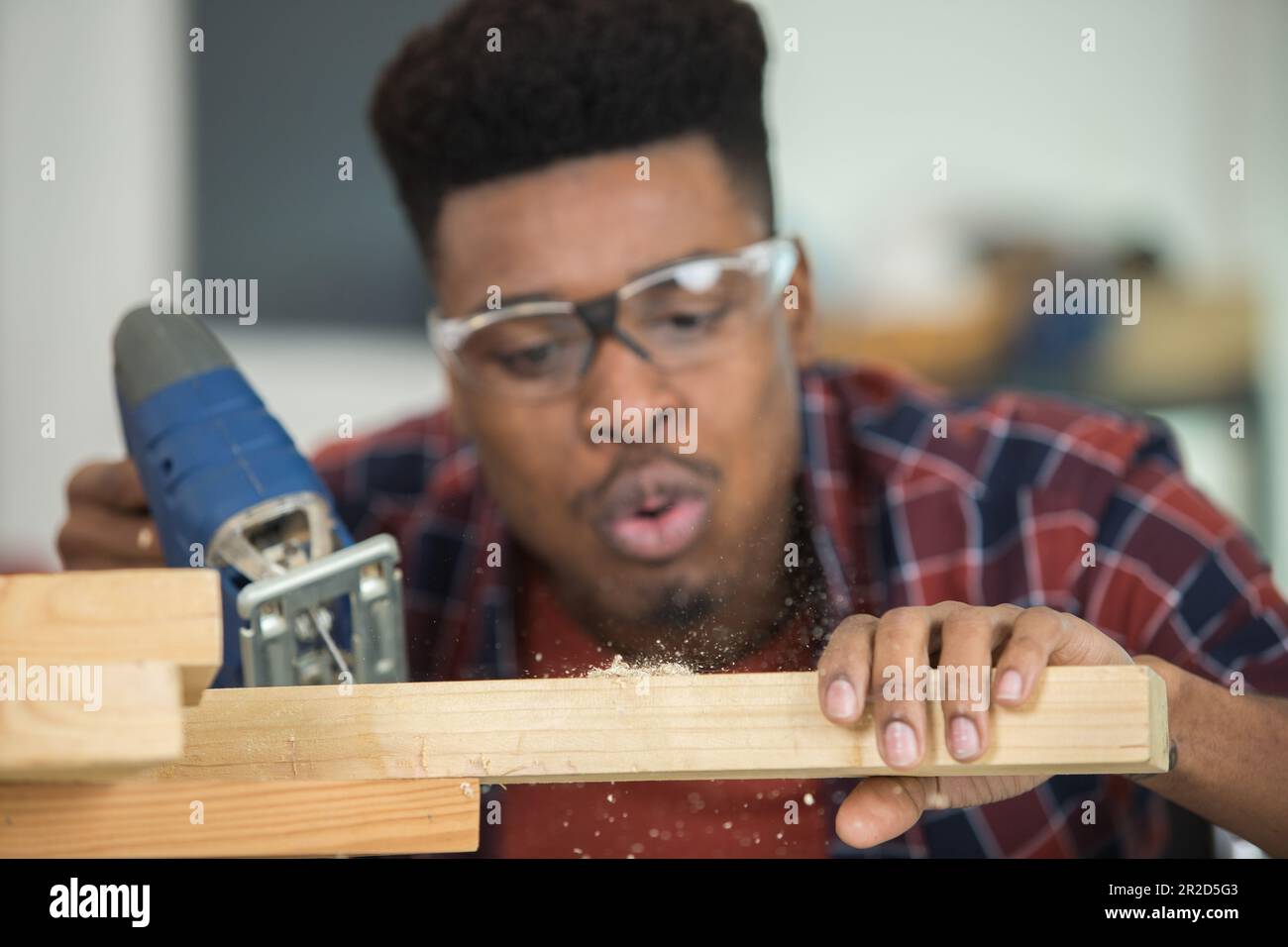 carpenter blows off wood dust cloud by wooden billet Stock Photo - Alamy