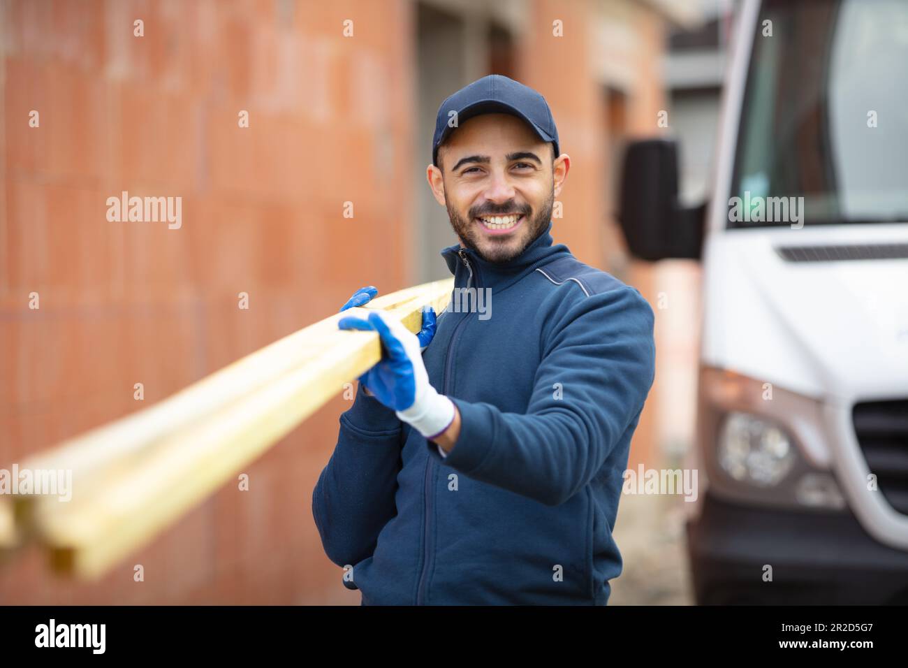 young carpenter carrying wood on shoulder at construction site Stock ...