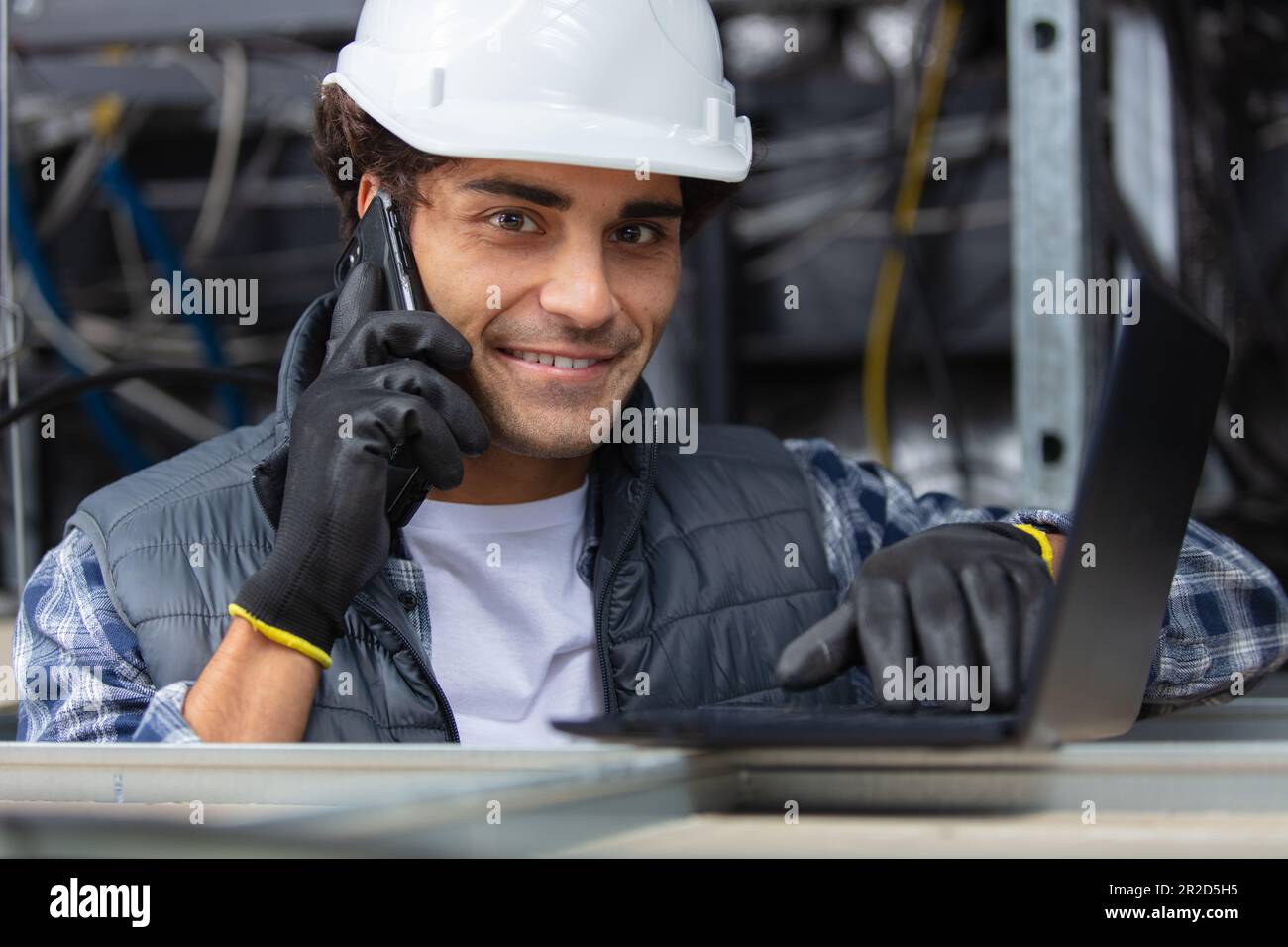 young electrician holding mobile phone while working Stock Photo - Alamy