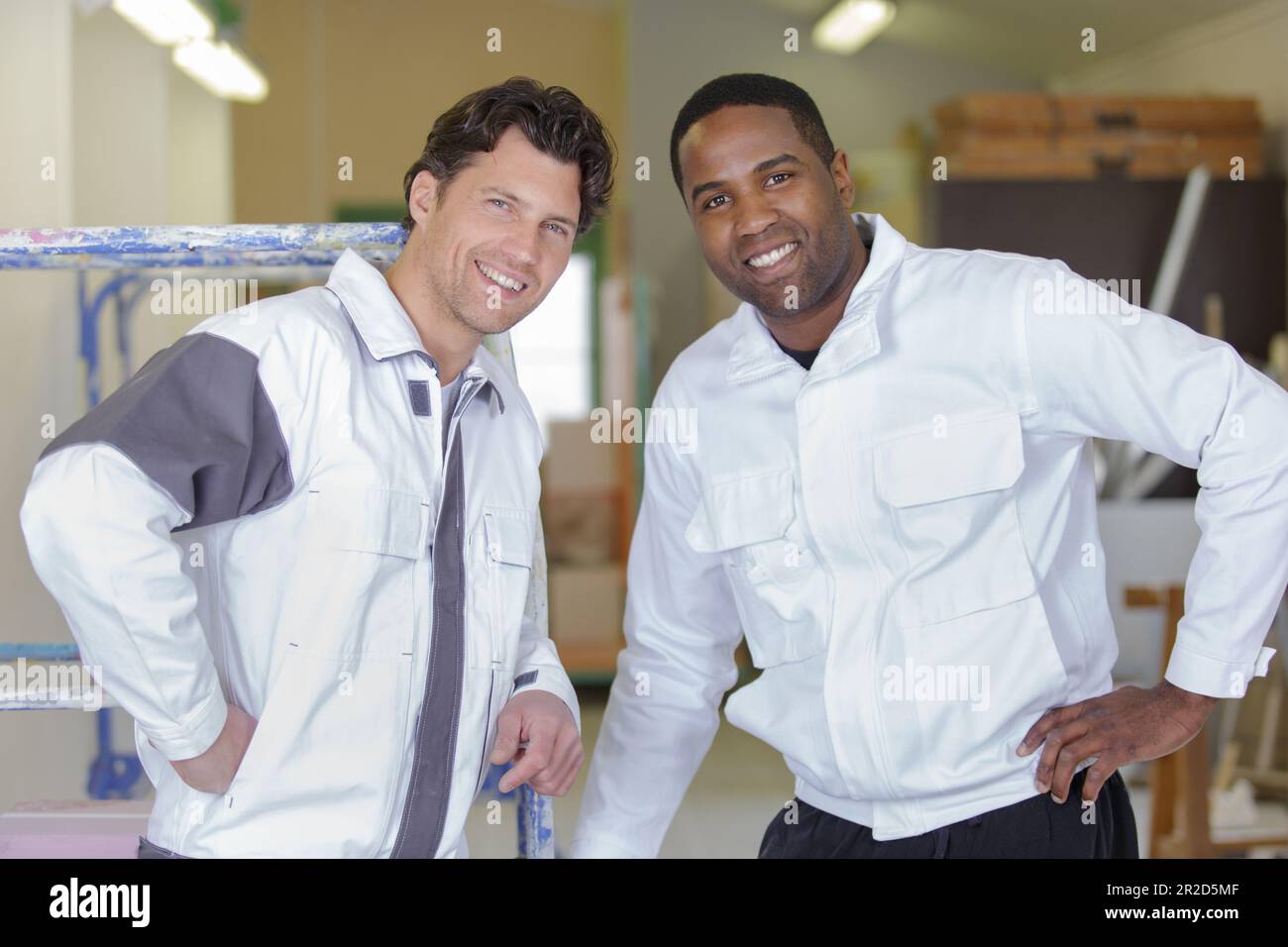 construction workers smiling after painting walls Stock Photo - Alamy