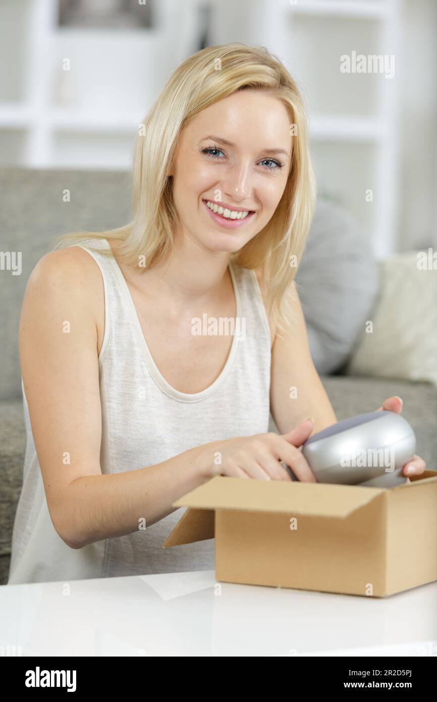happy young woman opening parcel indoors Stock Photo - Alamy