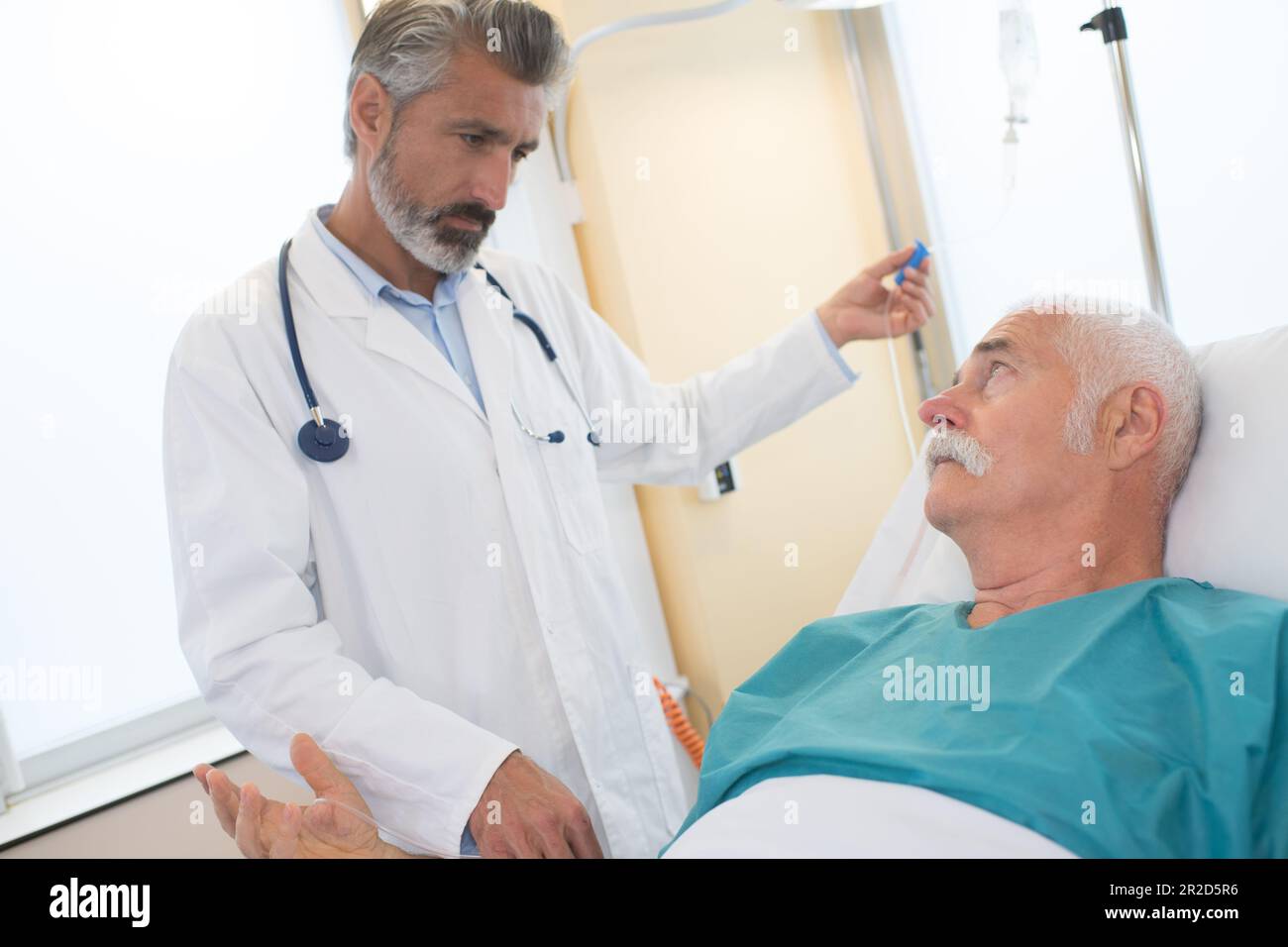 doctor in hospital room looking at patient Stock Photo - Alamy