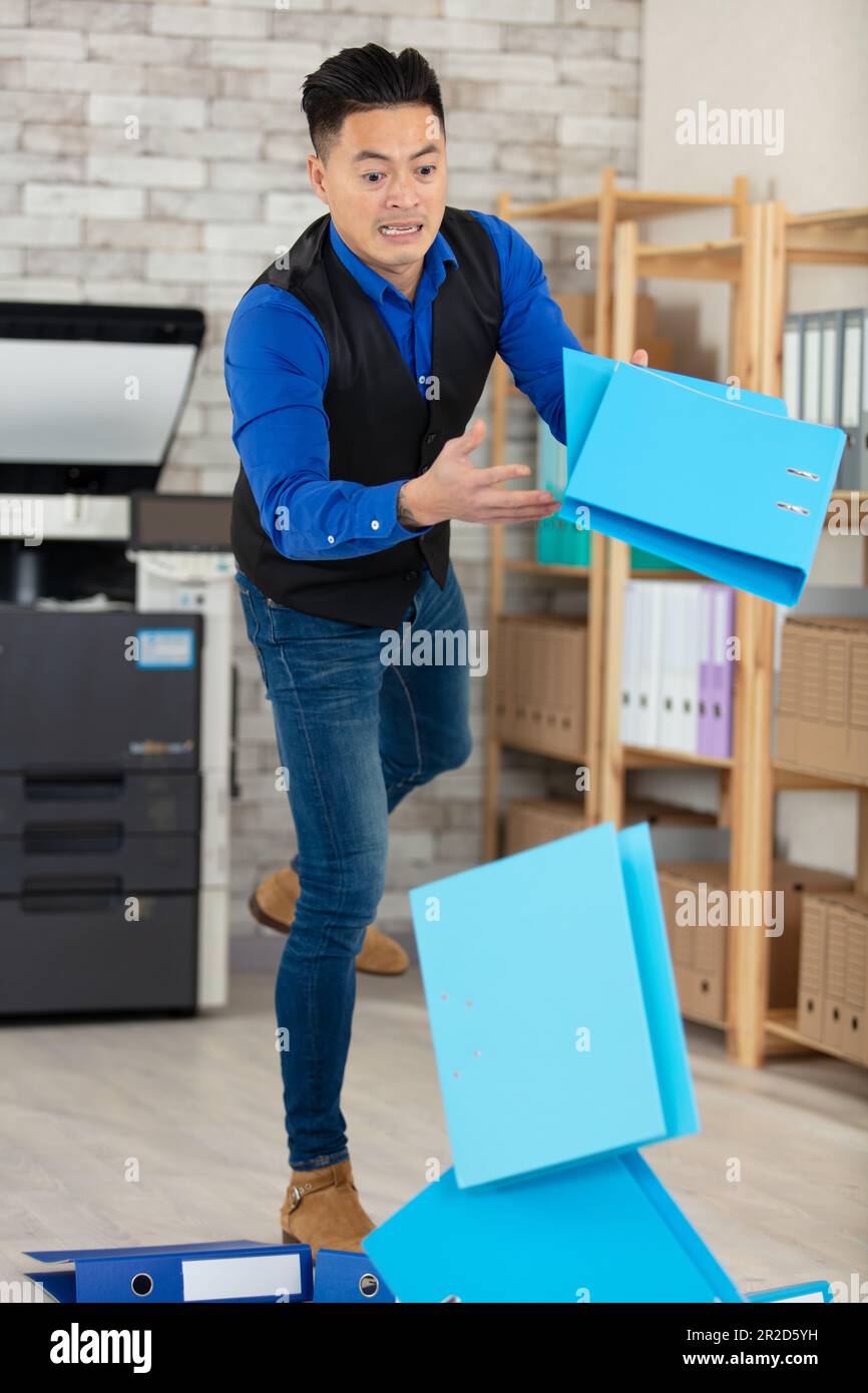 asian worker carrying files falling Stock Photo - Alamy