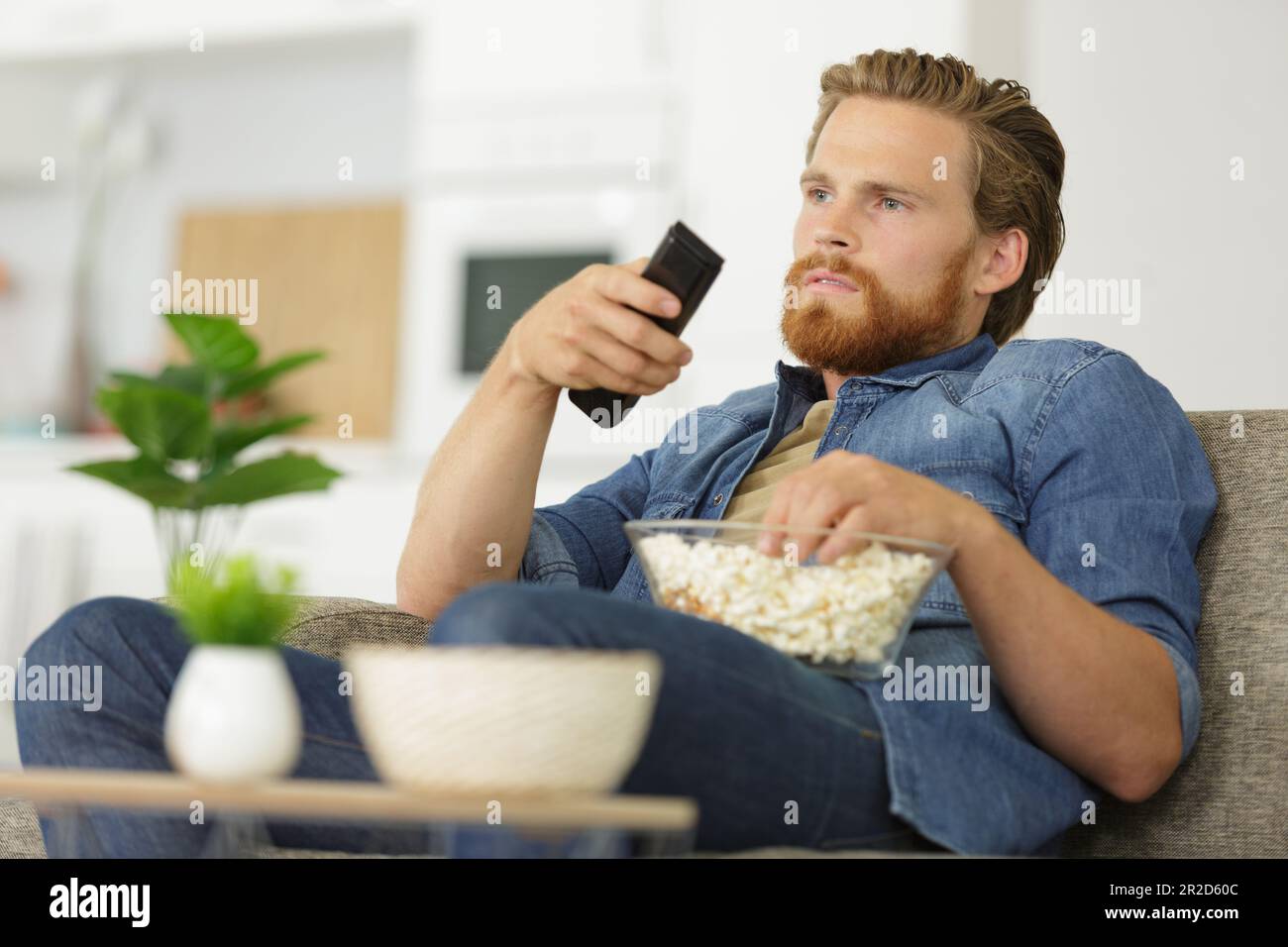single man eating popcorn while watching tv Stock Photo - Alamy