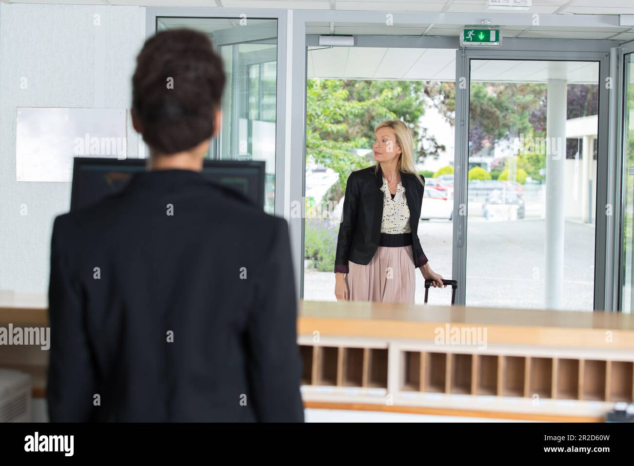 friendly young woman behind the reception desk welcoming customer ...