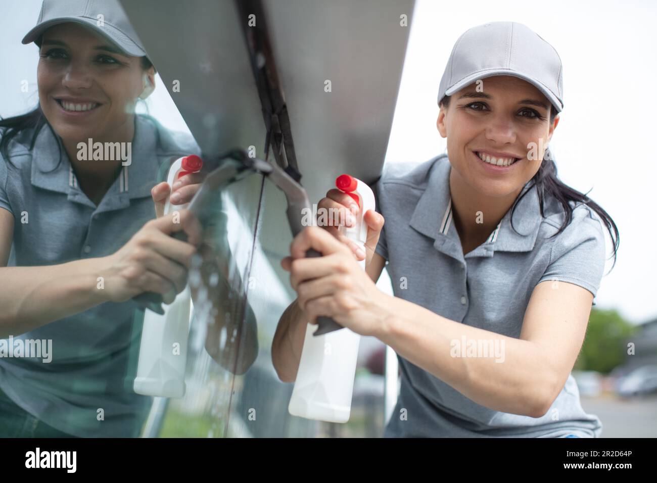 female window cleaner working outdoor with spray Stock Photo - Alamy