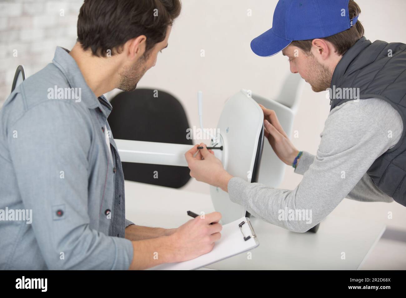 male apprentice assembling a chair under supervision Stock Photo - Alamy