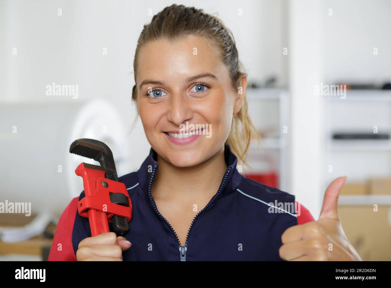 woman builder with tool shows thumb up Stock Photo - Alamy