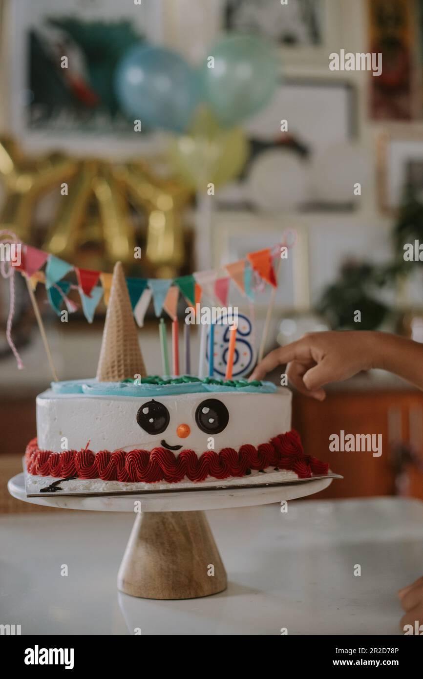 A snowman-themed, ice cream birthday cake with a finger dipping Stock ...