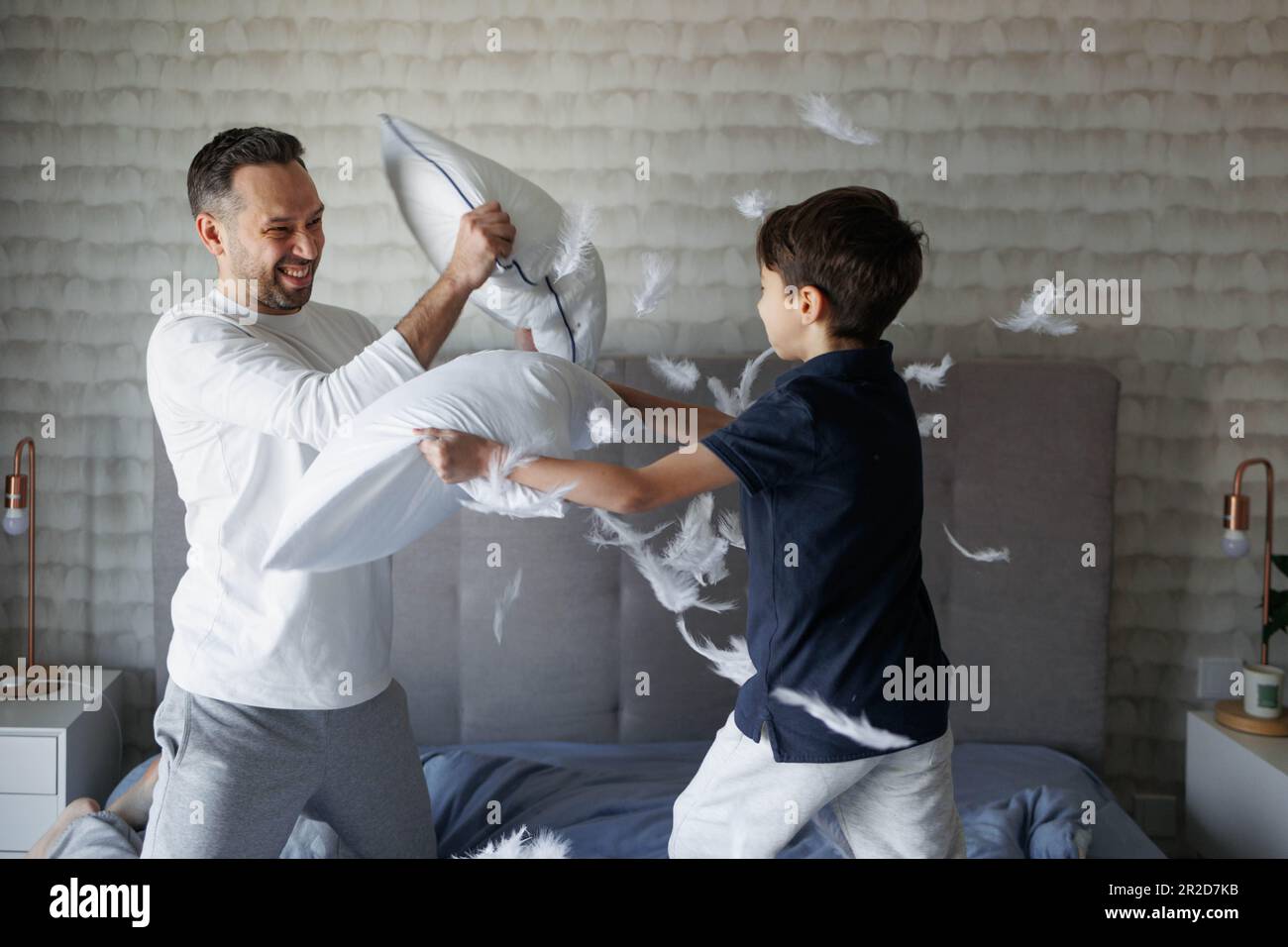 Dad and son play a pillow fight on the bed in the bedroom Stock Photo ...