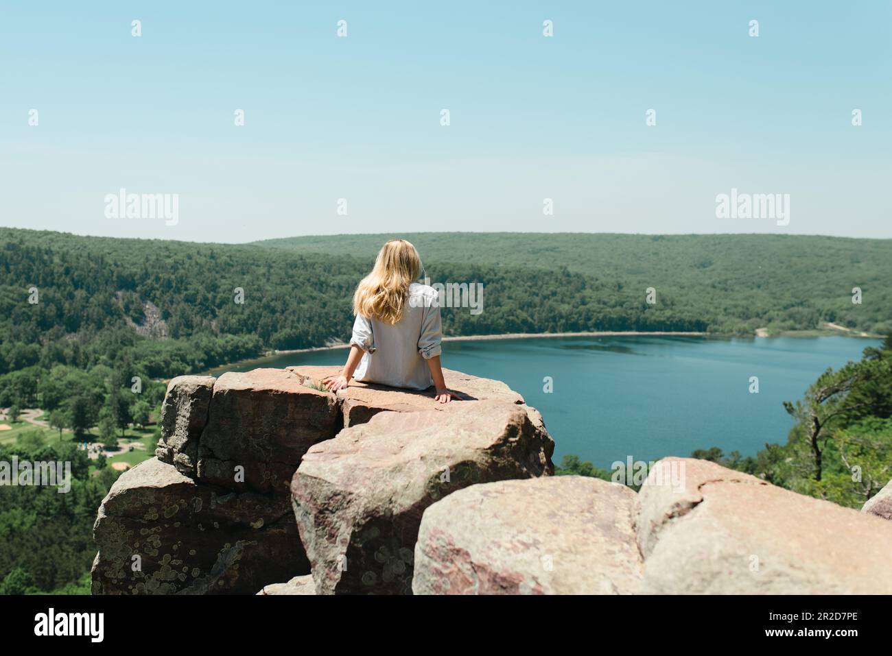 High angle of female sitting on cliff at Devil's Lake State Park, WI ...