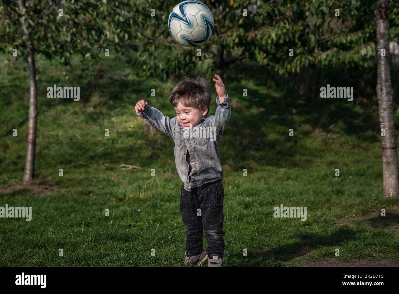 Happy kid in the grass throwing a soccer ball in the air. Sportive ...