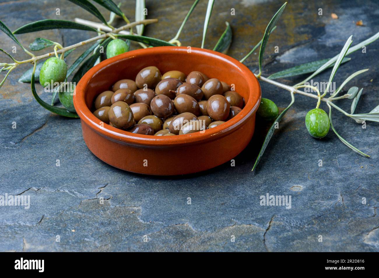 Olives in a clay dish, studio photograph with stone background. Still ...