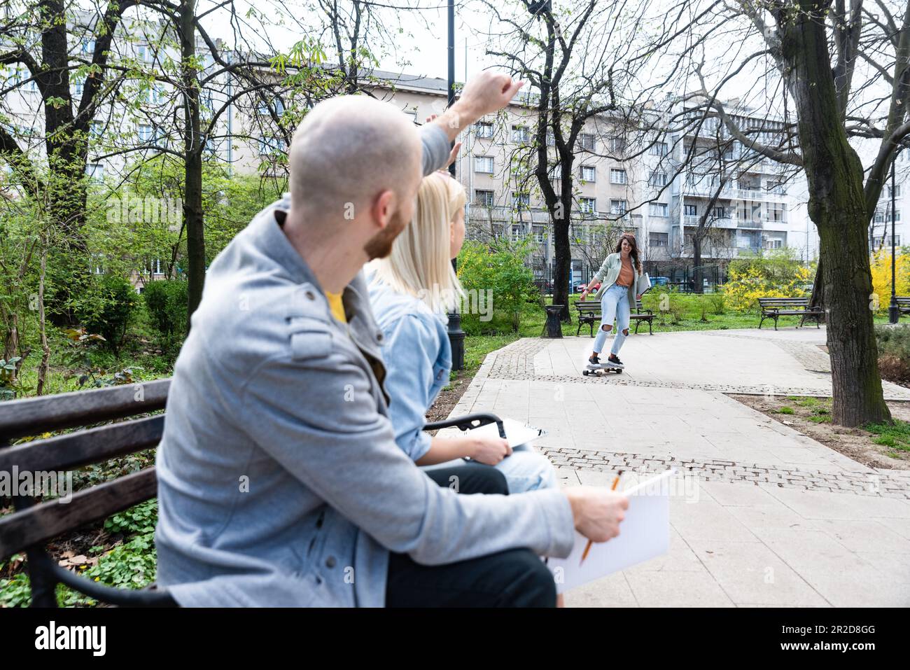 Cheerful classmates university students sitting on a bench in spring ...