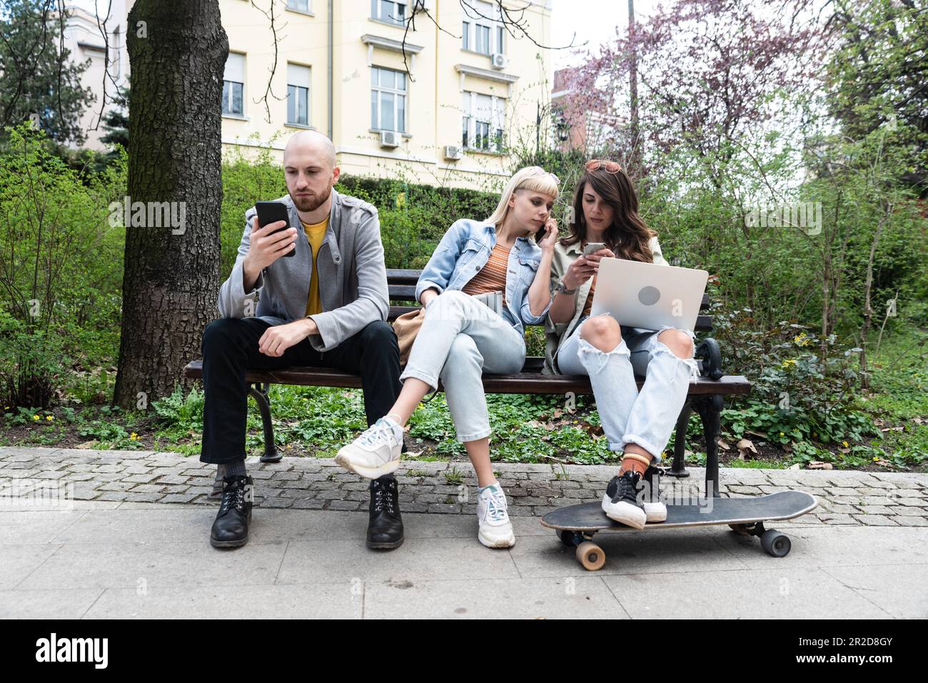 Cheerful classmates university students sitting on a bench in spring ...