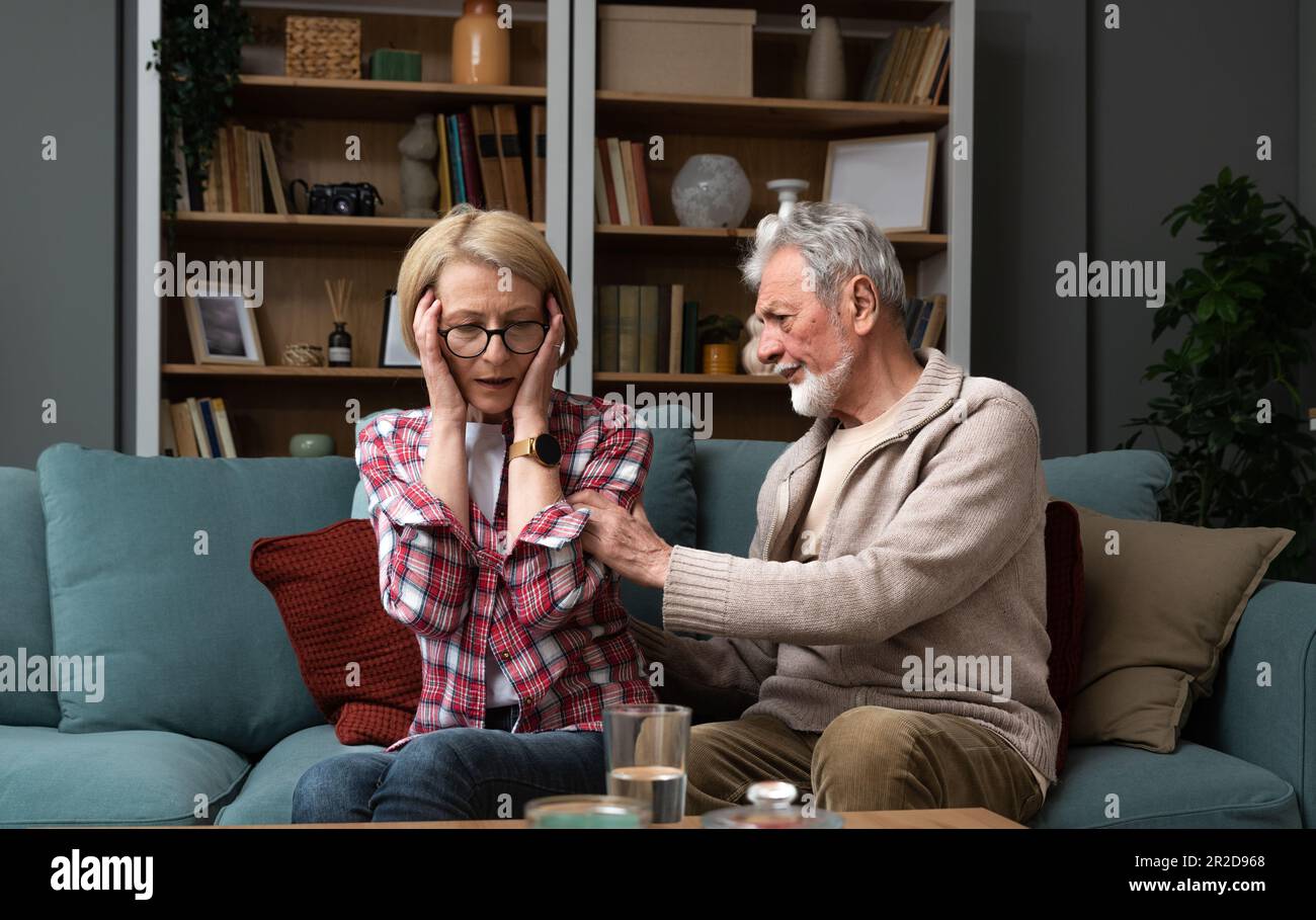 Portrait of senior couple in living room, Mature woman with pain in the ...