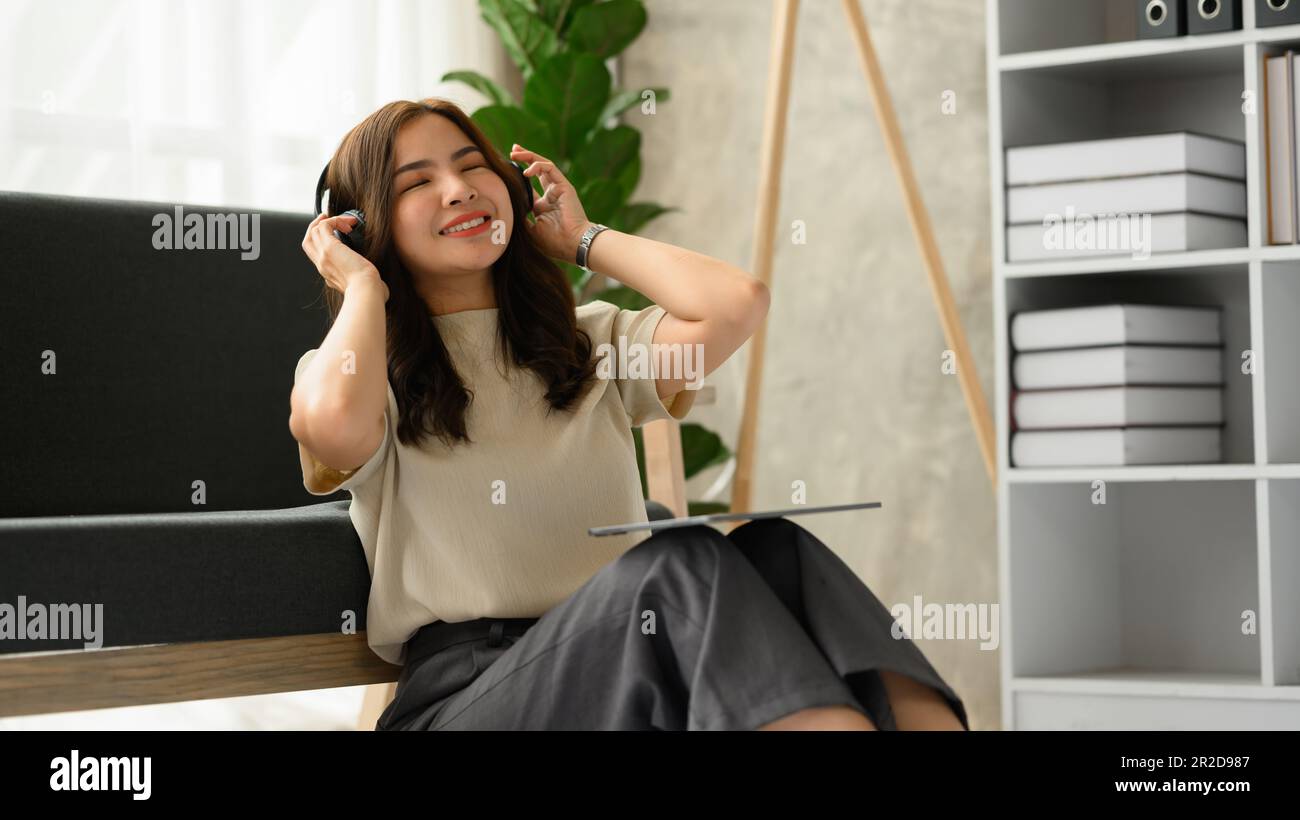 Relaxed young woman listening music on headphones with closed eyes ...