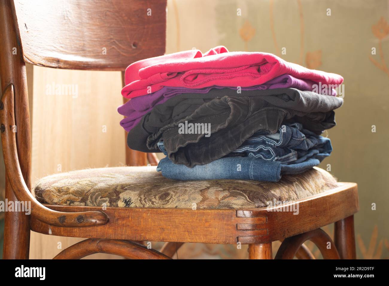a stack of folded clean clothes lies on a chair in the bedroom near the ...