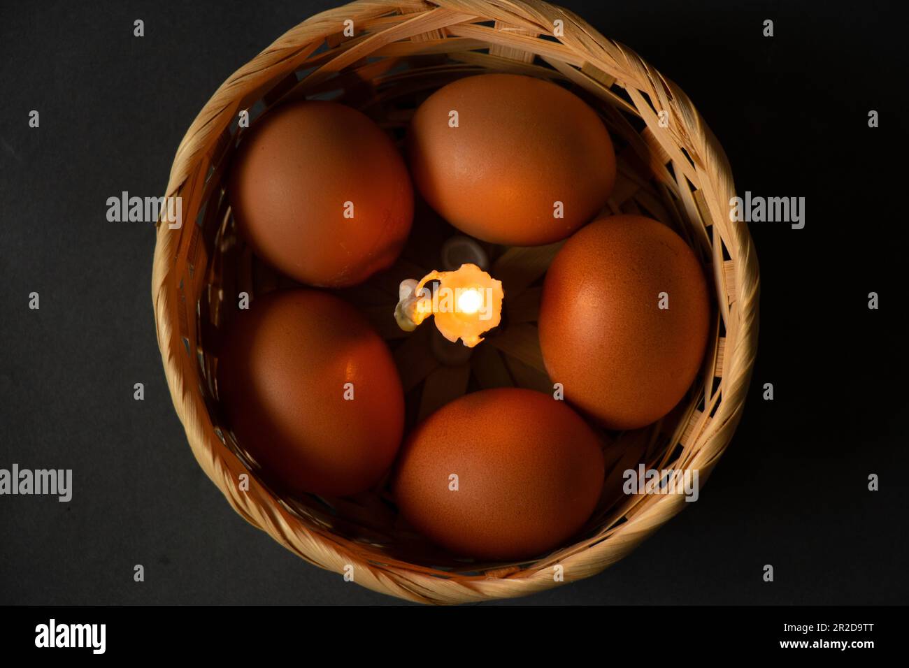 yellow chicken eggs and candle burning candle in a wicker straw basket ...