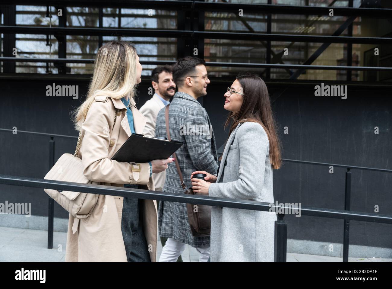 Group of business people walking outside in front of office building ...