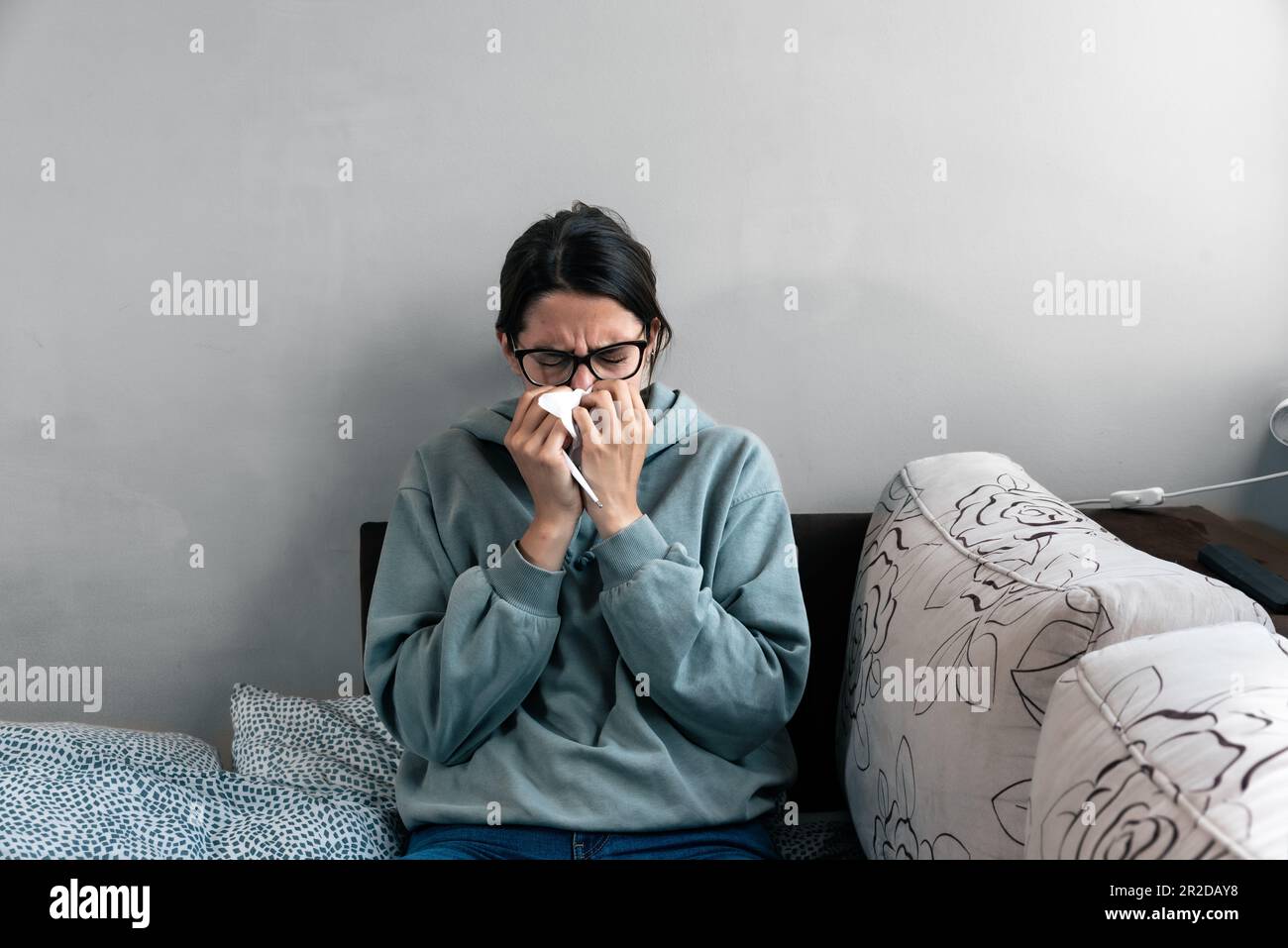 Ill upset young woman sitting on sofa covered with blanket freezing ...