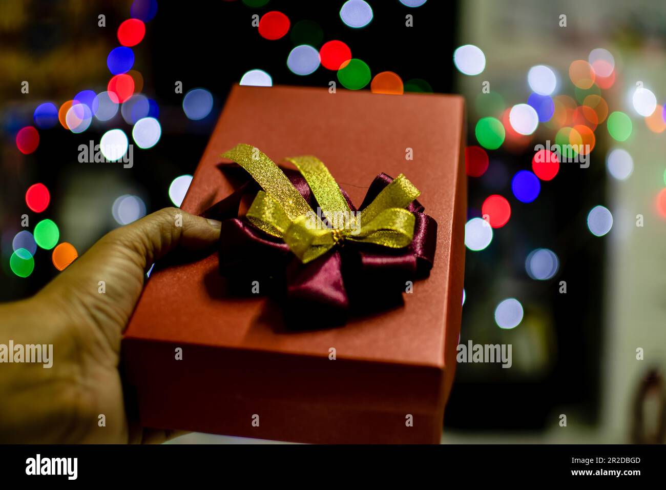 The hand of man holding red color Presents celebrates box with red and ...