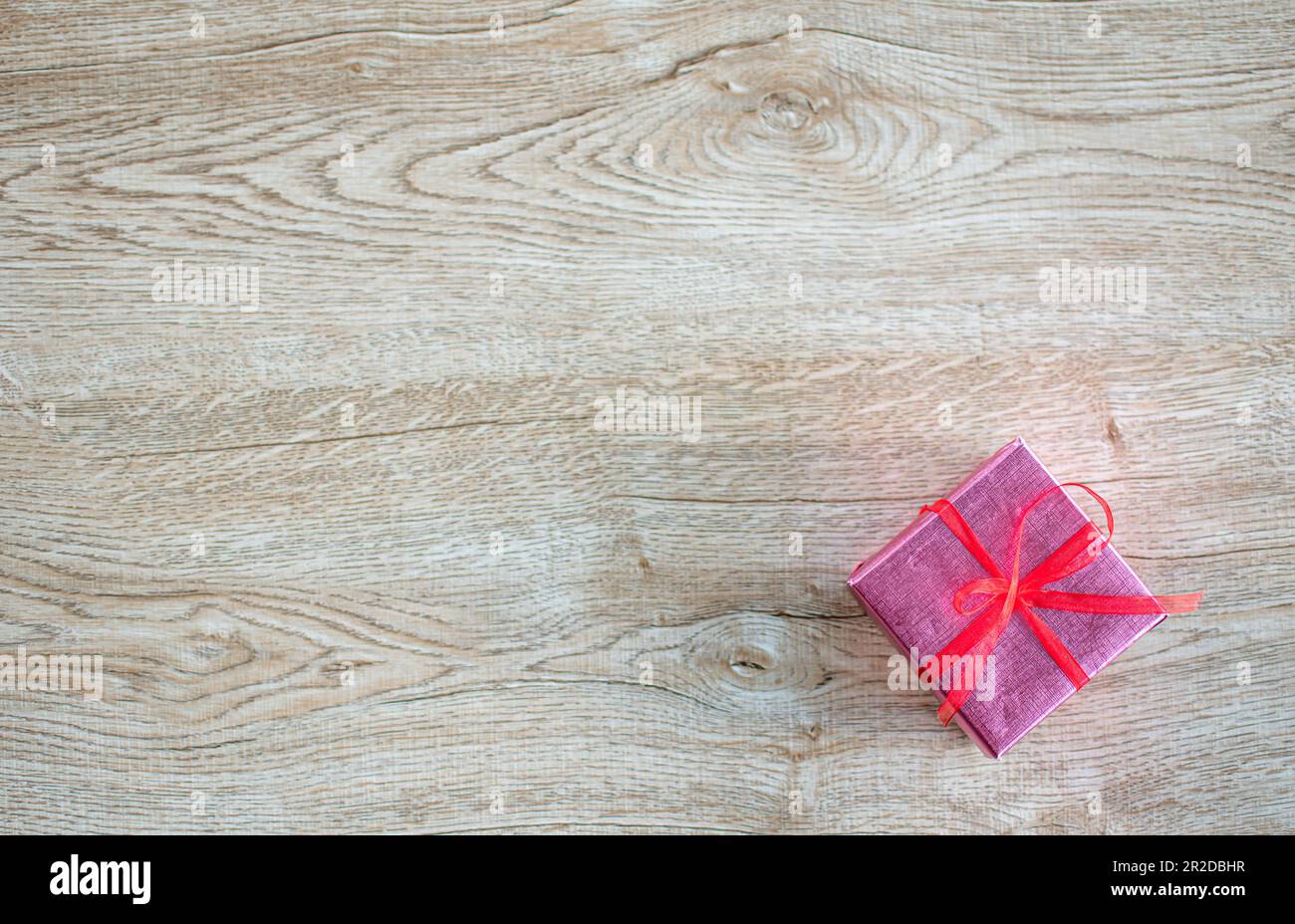 The pink current box a small has red ribbons placed on an old wooden ...