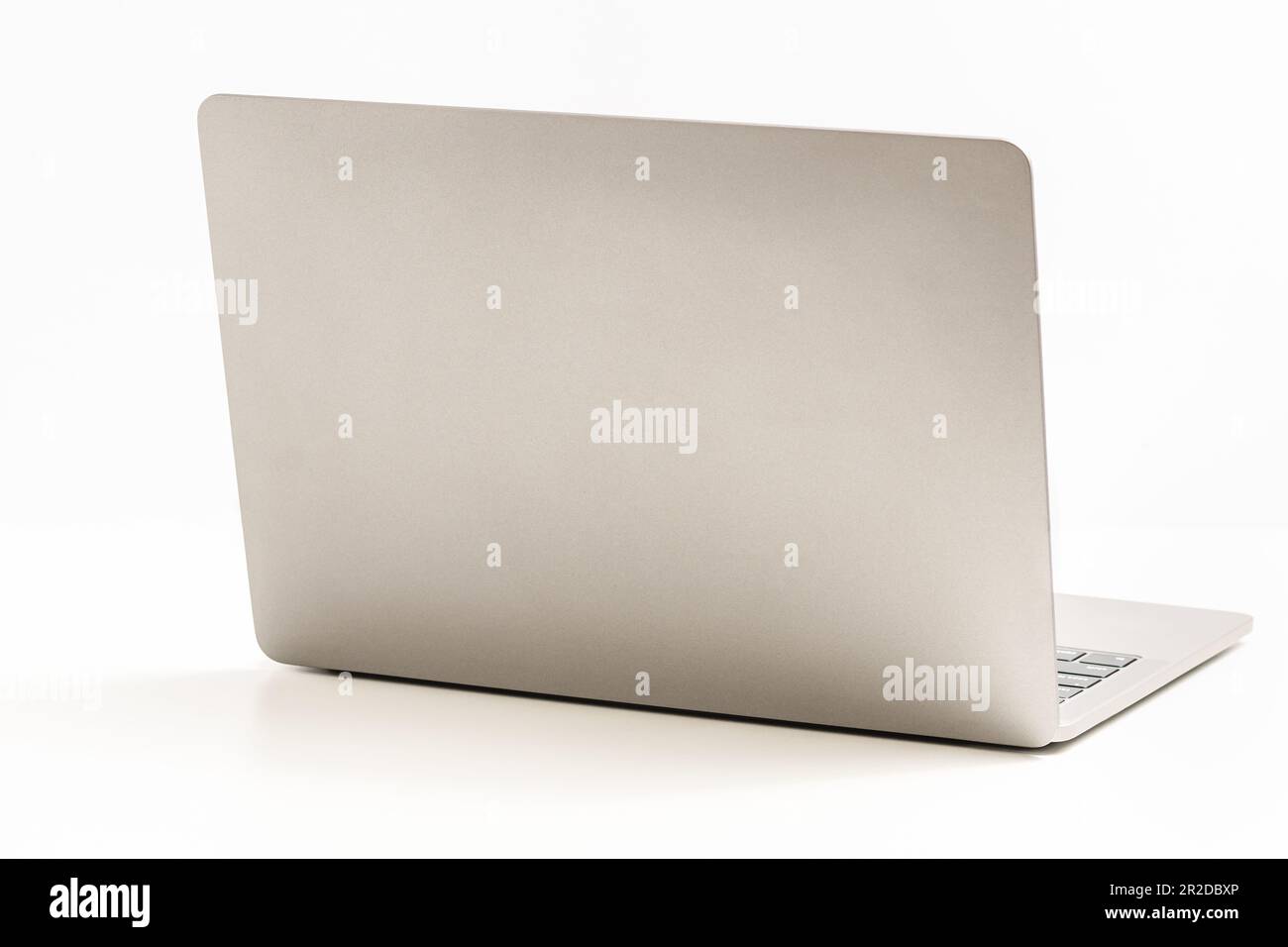 The back of the laptop is blank, placed on a white desk in an office ...