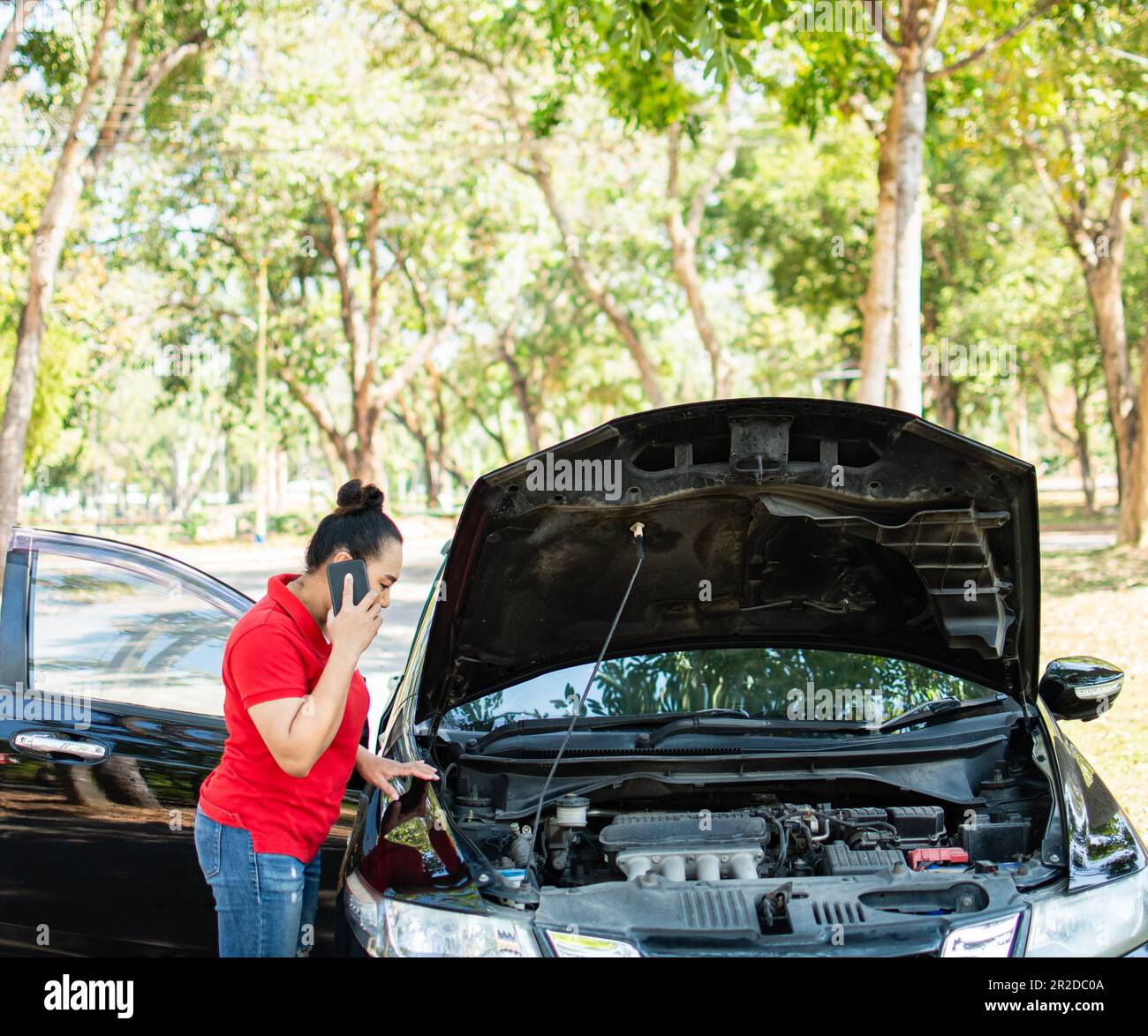 An anxious man stands and inspects a broken-down car in a rural ...